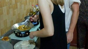 Uma cozinha com paredes azulejadas, bancada com uma frigideira, prato com comida e uma garrafa de óleo.