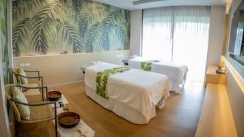 Quarto com duas camas, uma cadeira de massagem, piso de madeira e um grande mural na parede.
