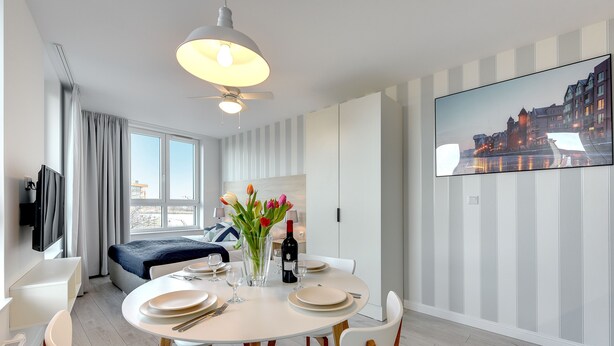 Quarto de hotel moderno com área de jantar, uma cama, televisão e vista para a cidade.