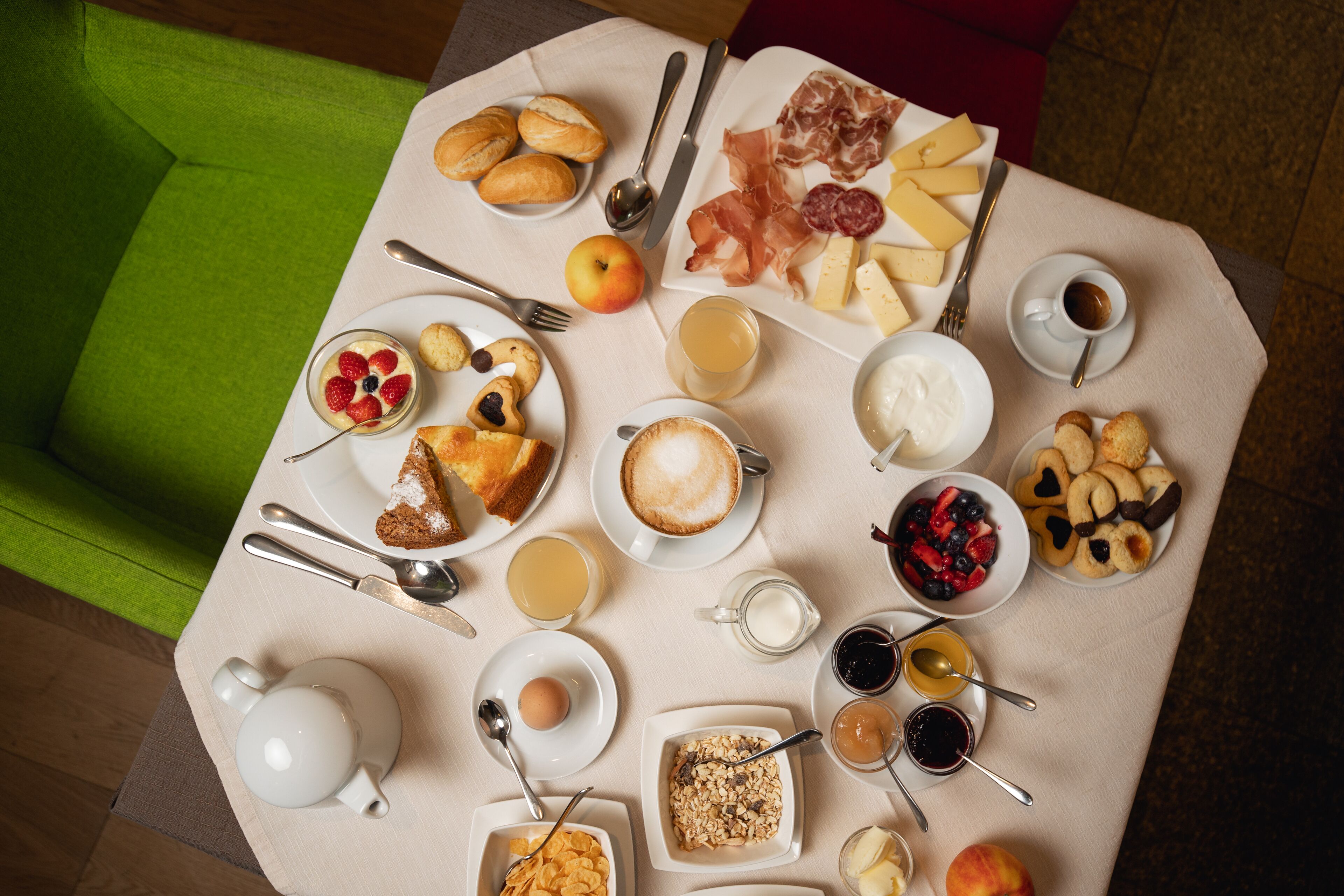 Uma mesa de café da manhã com diversos alimentos, utensílios e uma chaleira.