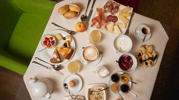 Uma mesa de café da manhã com diversos alimentos, utensílios e uma chaleira.