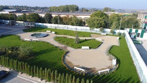 Jardim ajardinado com um espelho d'água circular, bancos e um caminho pavimentado.