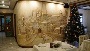 Uma área de refeições com um mural entalhado na parede, uma árvore de Natal e uma mesa posta para dois.