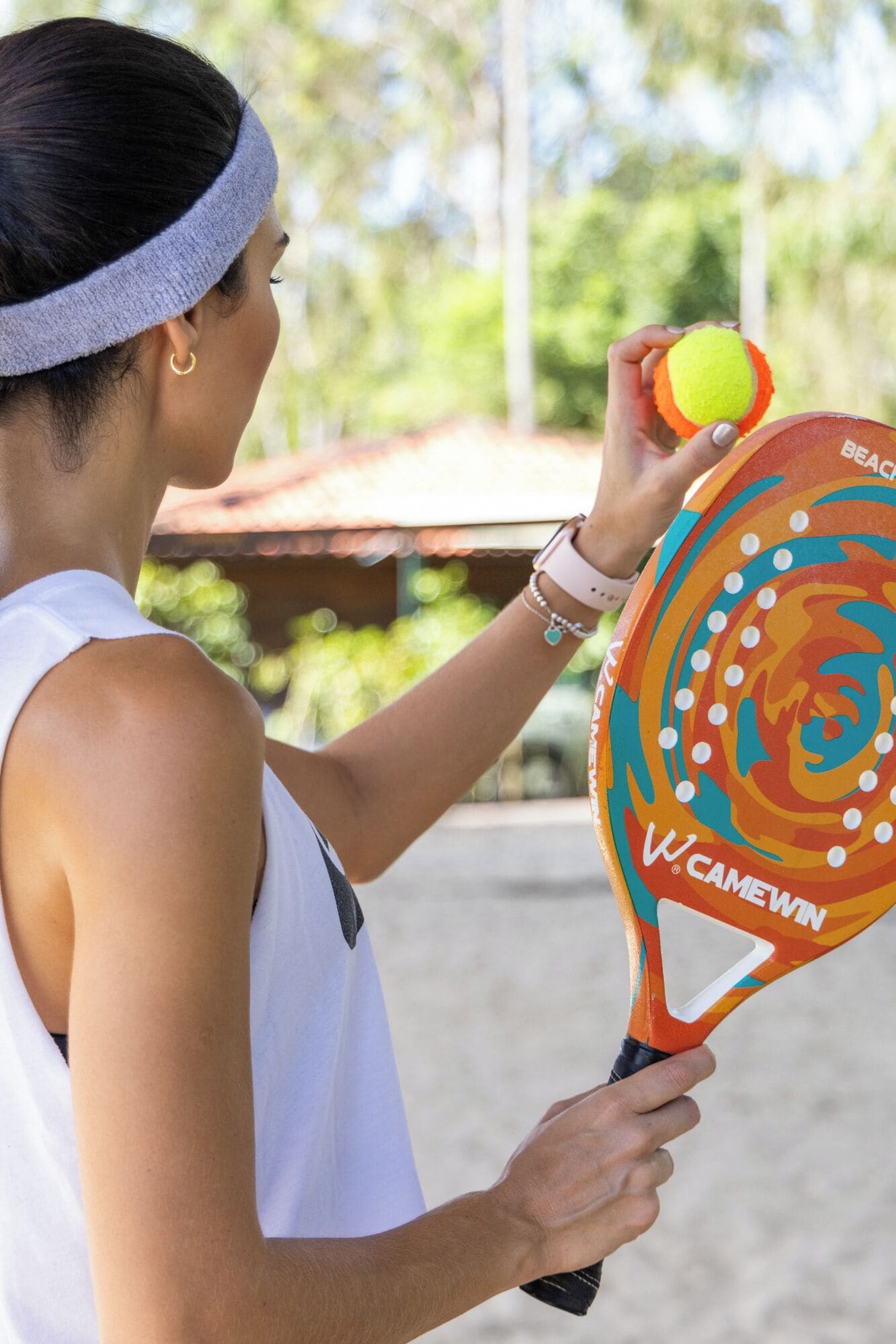 Uma pessoa segurando uma raquete colorida e uma bola amarela, provavelmente praticando um esporte.
