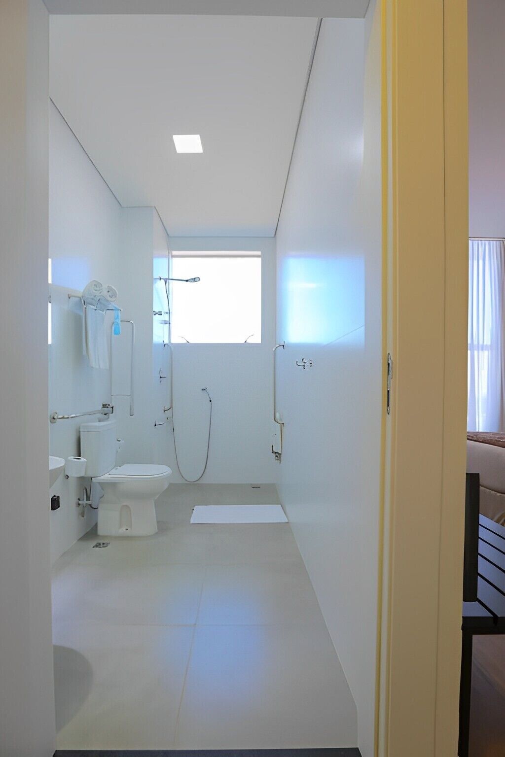 Casa de banho moderna com sanita, bidé e chuveiro. Há uma janela que permite a entrada de luz natural.