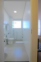 Casa de banho moderna com sanita, bidé e chuveiro. Há uma janela que permite a entrada de luz natural.