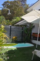Um quintal com piscina, cerca de madeira e um guarda-sol de patío.