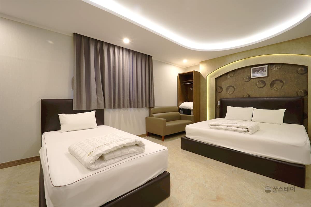 Quarto de hotel com duas camas, área de estar e guarda-roupa.
