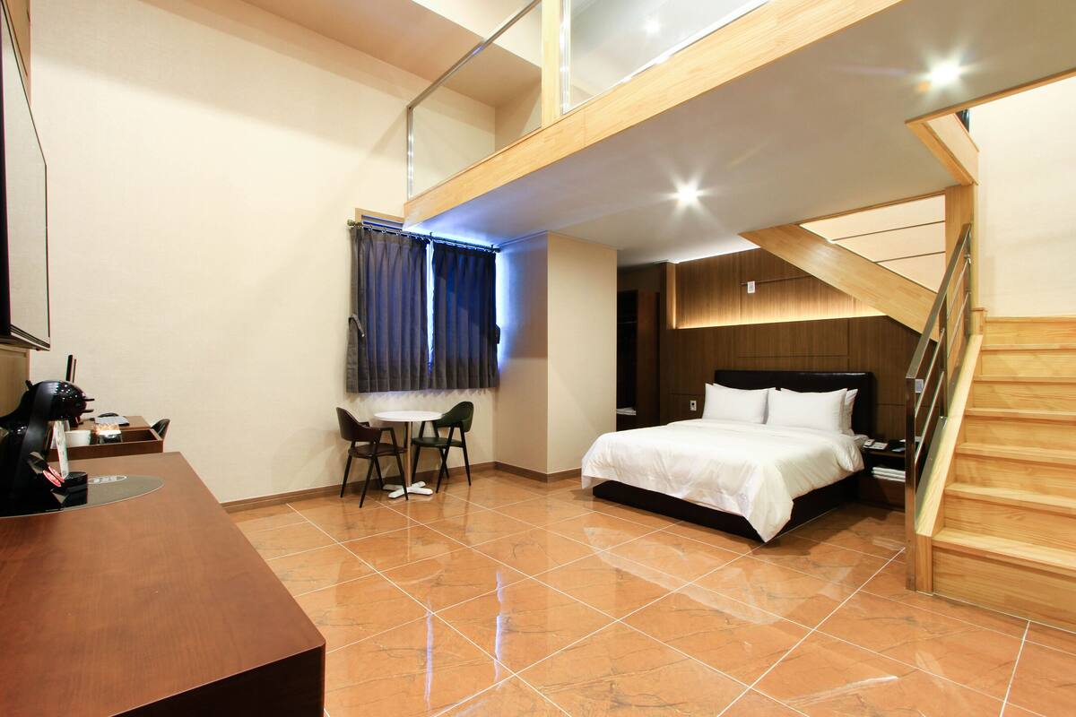 Quarto de hotel moderno com cama, escrivaninha e cadeira.