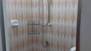 Uma casa de banho pequena com chuveiro, sanita e secador de mãos.