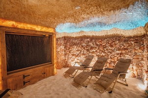 Quarto com parede de pedra, um armário de madeira e três poltronas reclináveis.
