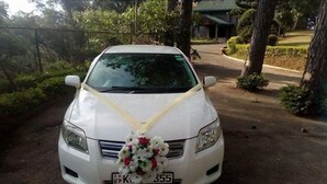 Um carro branco com decoração floral no capô e uma placa de identificação.
