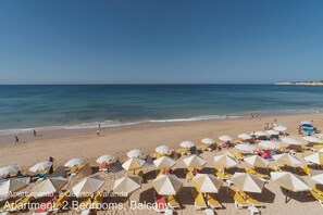 Uma praia com guarda-sóis e espreguiçadeiras.