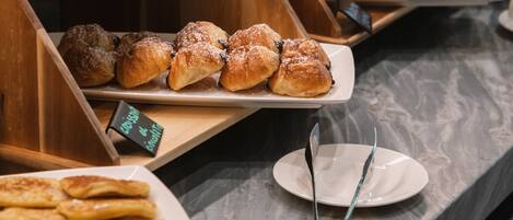 Buffet com diversos produtos de panificação, como pastéis e muffins.