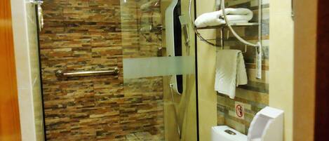 Uma casa de banho moderna com cabine de duche em vidro, sanita branca e barra de toalhas.