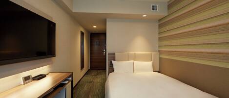 Quarto de hotel com cama, televisão, escrivaninha e televisão na parede.