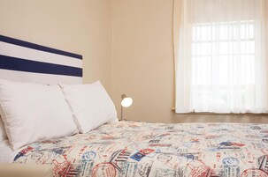 Uma cama com cabeceira listrada, travesseiro branco e cobre com padrão.