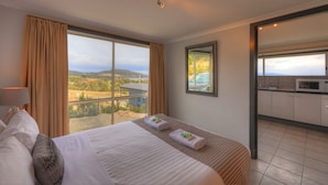 Quarto de hotel com uma cama grande, vista para o campo, cozinha e um espelho na parede.