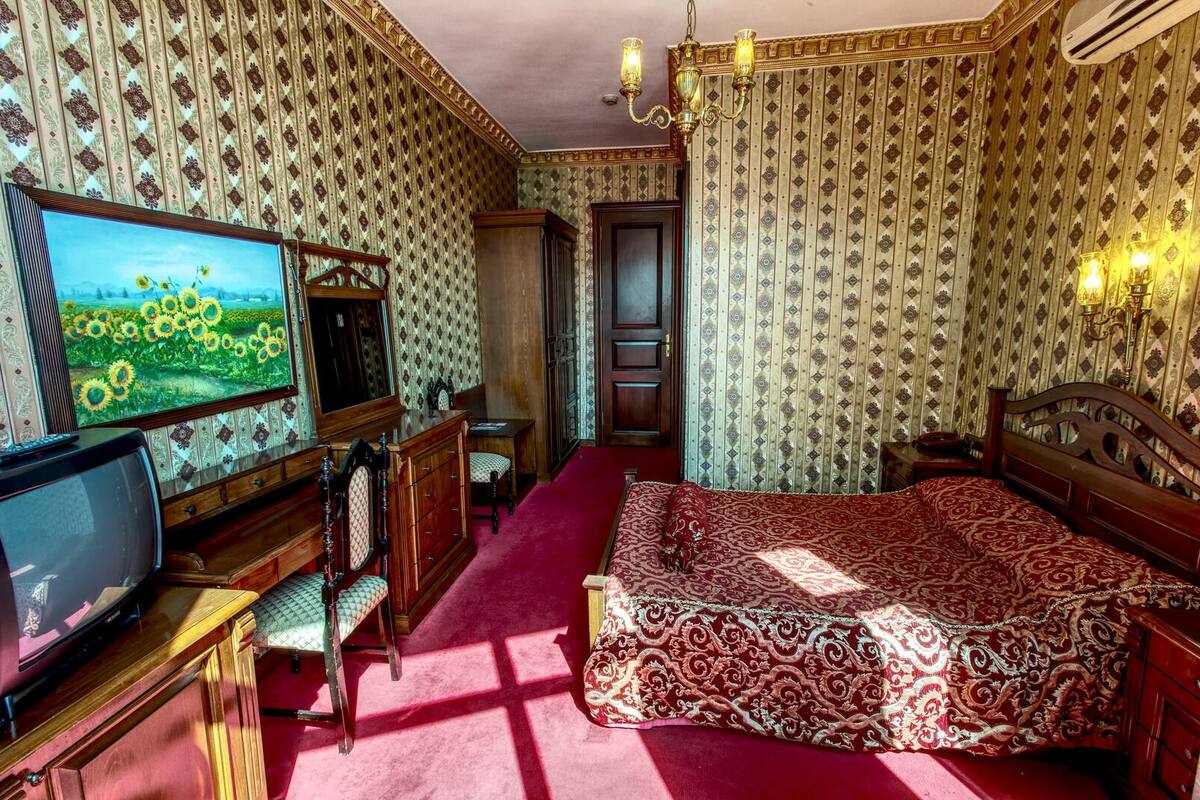 Quarto com cama grande, televisão, cómoda e guarda-roupa.