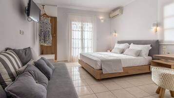 Quarto moderno com cama, sofá, televisão e janela com cortinas.