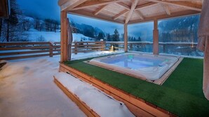 Uma cabana de madeira com hidromassagem e vista para uma paisagem nevada.