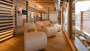 Um spa moderno com ripas de madeira, duas poltronas brancas acolchoadas e uma grande janela com vista para o exterior.