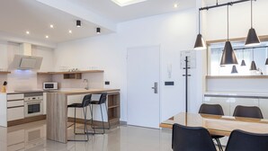 Uma cozinha moderna com ilha central, área de refeições com mesa e cadeiras de madeira, e iluminação pendente.