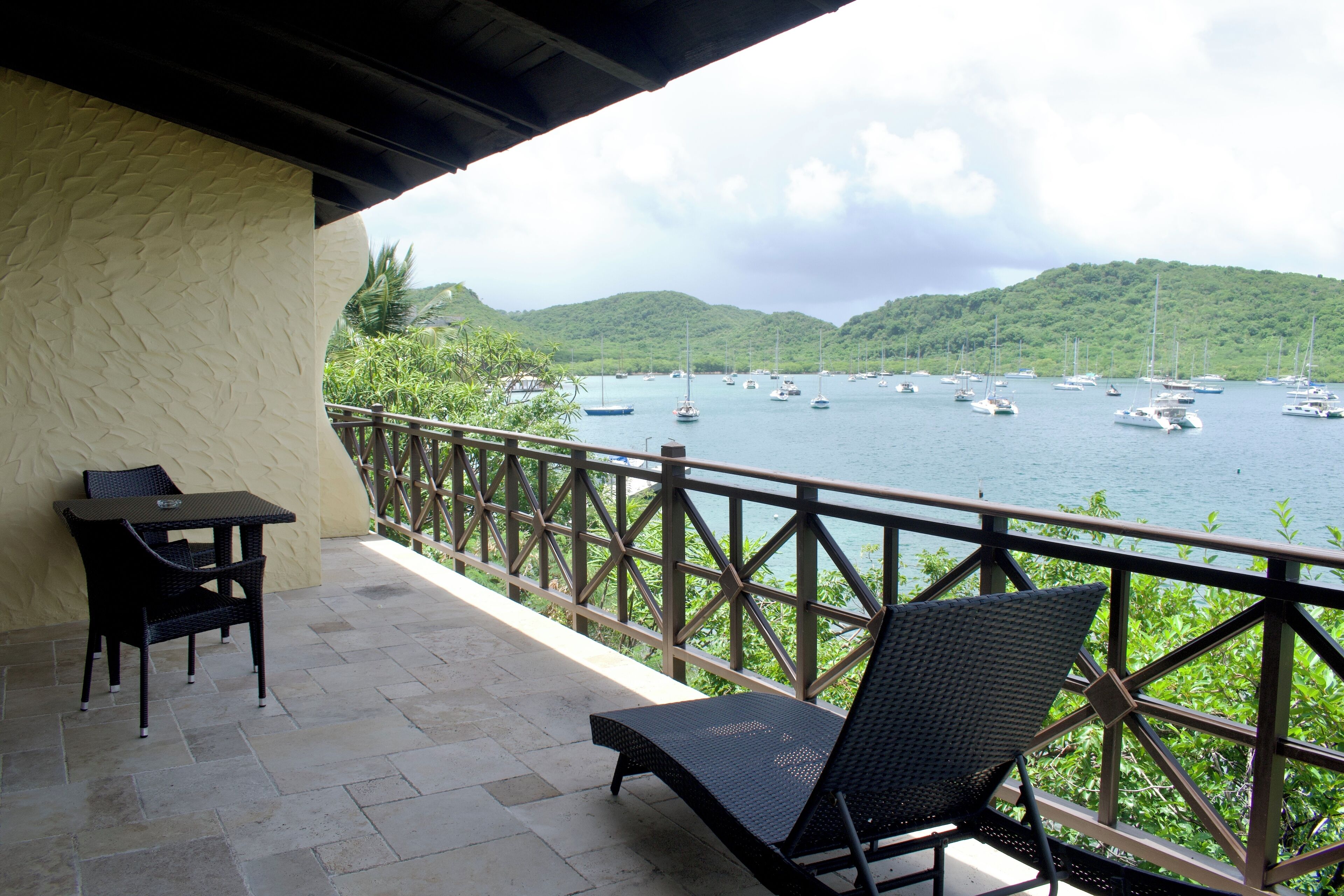 Varanda com mesa e cadeiras com vista para uma marina e barcos.