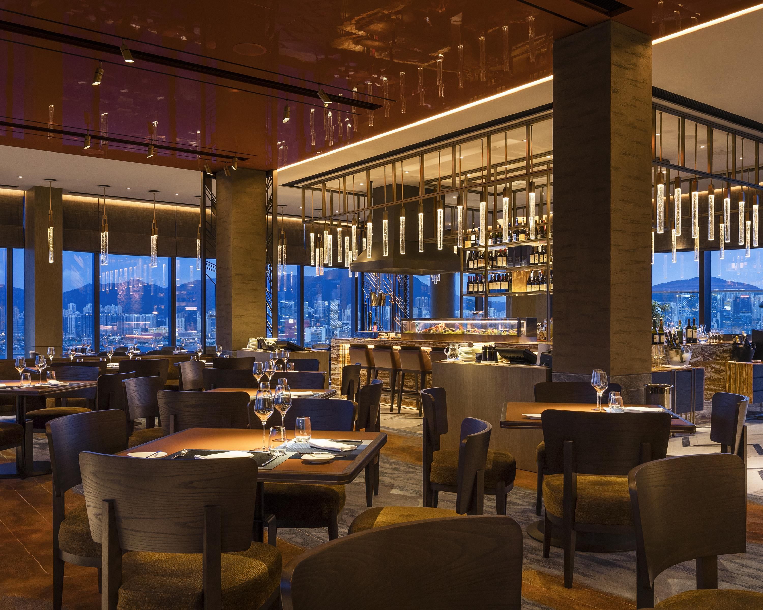 Um restaurante moderno com mesas, cadeiras, um bar e grandes janelas com vista para a cidade.