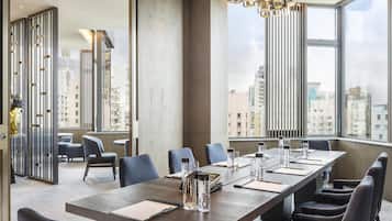Uma sala de conferências moderna com uma mesa comprida, cadeiras e vista para a cidade.
