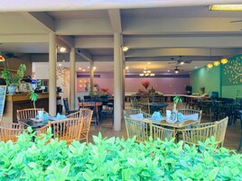 Um restaurante amplo com várias áreas de refeição, incluindo uma mesa redonda central e diversas mesas menores.