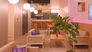 Interior moderno com assentos, área de bar e sinalização indicando serviços de alimentação e bebidas.