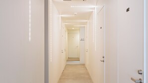 Um corredor estreito e bem iluminado, com carpete bege e paredes brancas, que leva a uma porta com o número 402.
