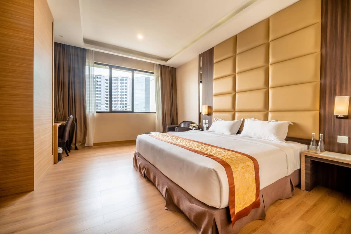 Quarto de hotel com cama grande, piso de madeira, vista para edifícios altos e design moderno.