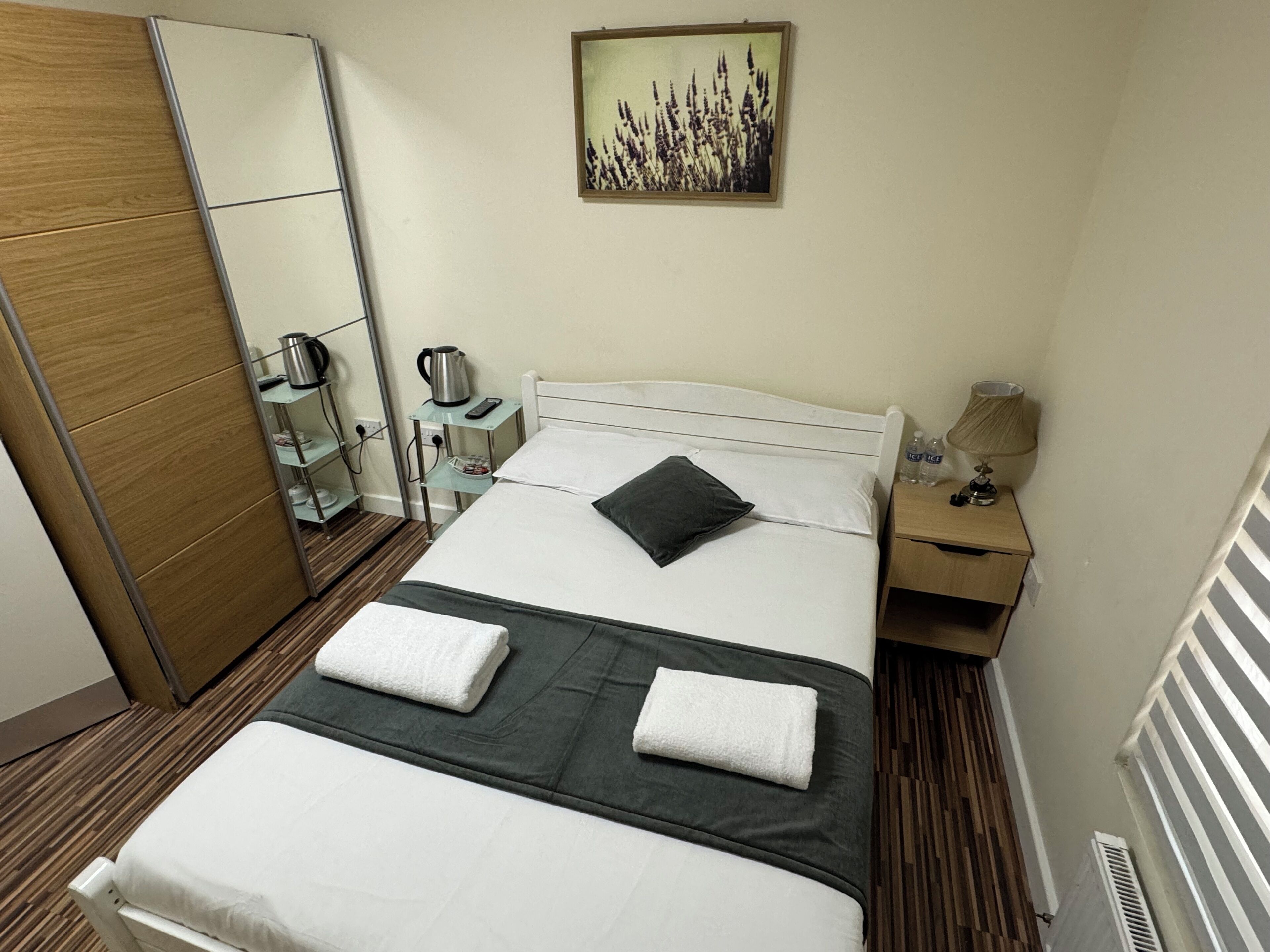 Quarto de hotel bem arrumado com cama, mesas de cabeceira, espelho e um quadro na parede.