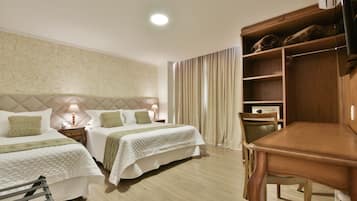 Quarto de hotel com duas camas, uma escrivaninha de madeira, uma cadeira, um guarda-roupa e uma mesa de cabeceira com luminárias.