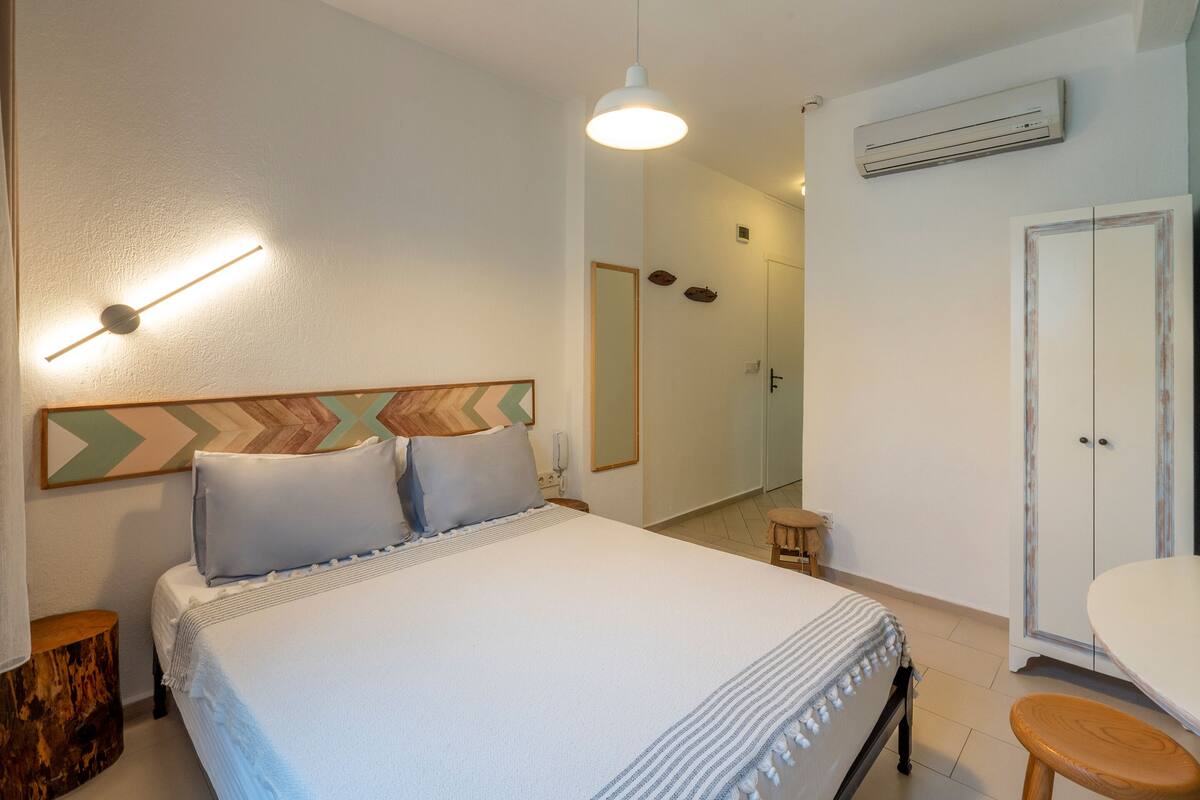 Quarto bem arrumado com cama, mesa de cabeceira e guarda-roupa.