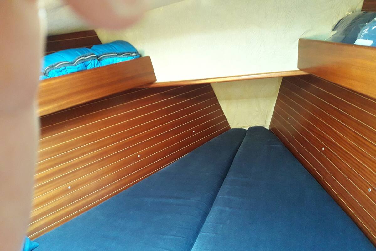 Um interior compacto, em madeira, com um banco acolchoado azul e uma mesa pequena.