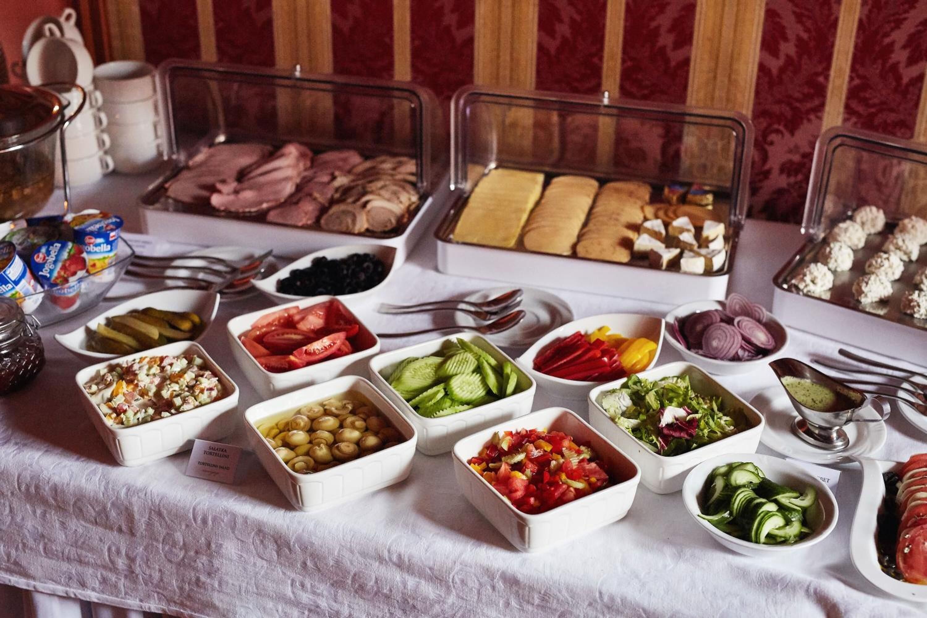 Buffet com diversas opções de comida, incluindo carnes, queijos, saladas e frutas.