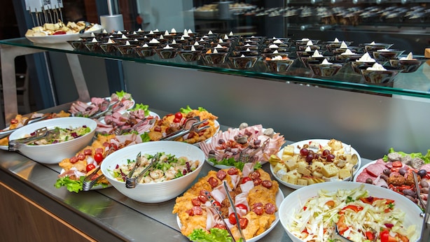 Buffet com diversos pratos, incluindo saladas, carnes e sobremesas.