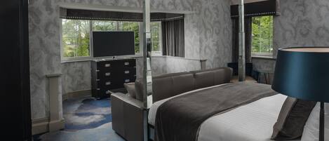 Quarto com cama, televisão, cômoda e janela.
