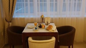 Uma sala de jantar com uma mesa posta para dois, um vaso com flores e um menu.