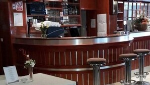 Um restaurante com balcão curvo, banquetas de bar e uma mesa com cardápio.