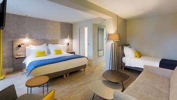 Quarto de hotel com cama grande, mesas de cabeceira, escrivaninha, sofá e abajur.