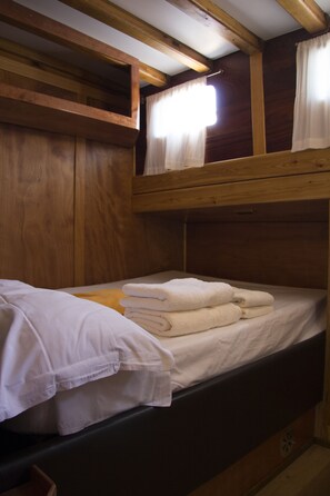 Uma cama beliche com roupa de cama branca e uma janela com cortinas.