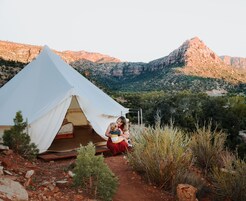 Uma tenda montada em paisagem natural, com montanhas ao fundo.