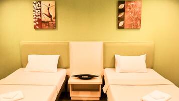 Quarto de hotel com duas camas, uma mesa de cabeceira e obras de arte nas paredes.
