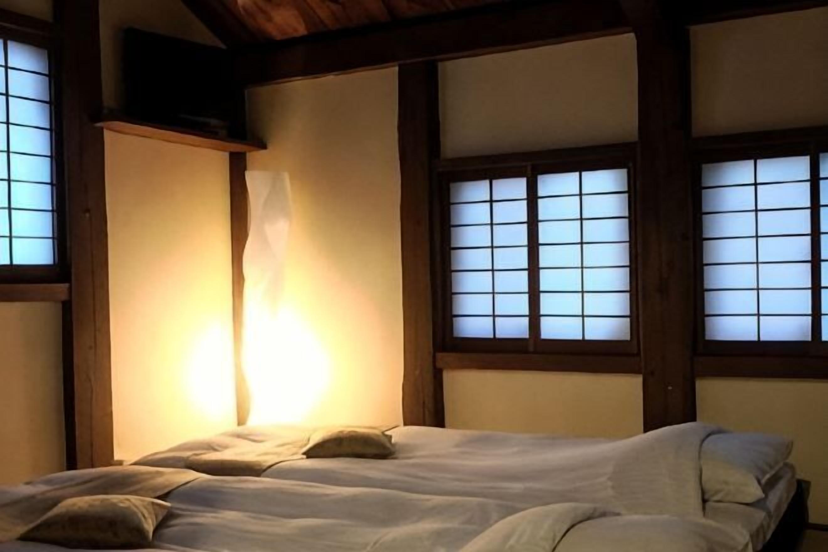 Um quarto em estilo tradicional japonês, com tatames, cama de madeira baixa e portas shoji.