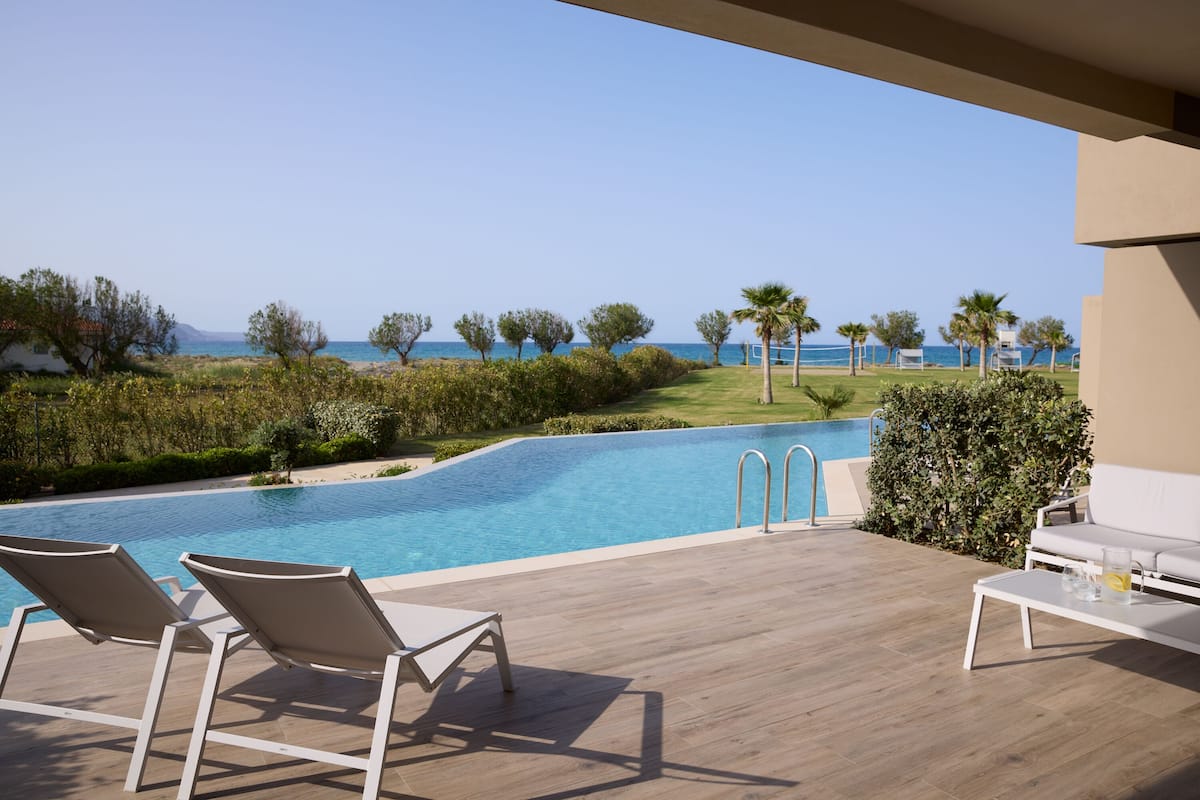 Área da piscina com espreguiçadeiras e vista para o mar.