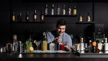 Bar com diversas garrafas e um bartender preparando bebidas.